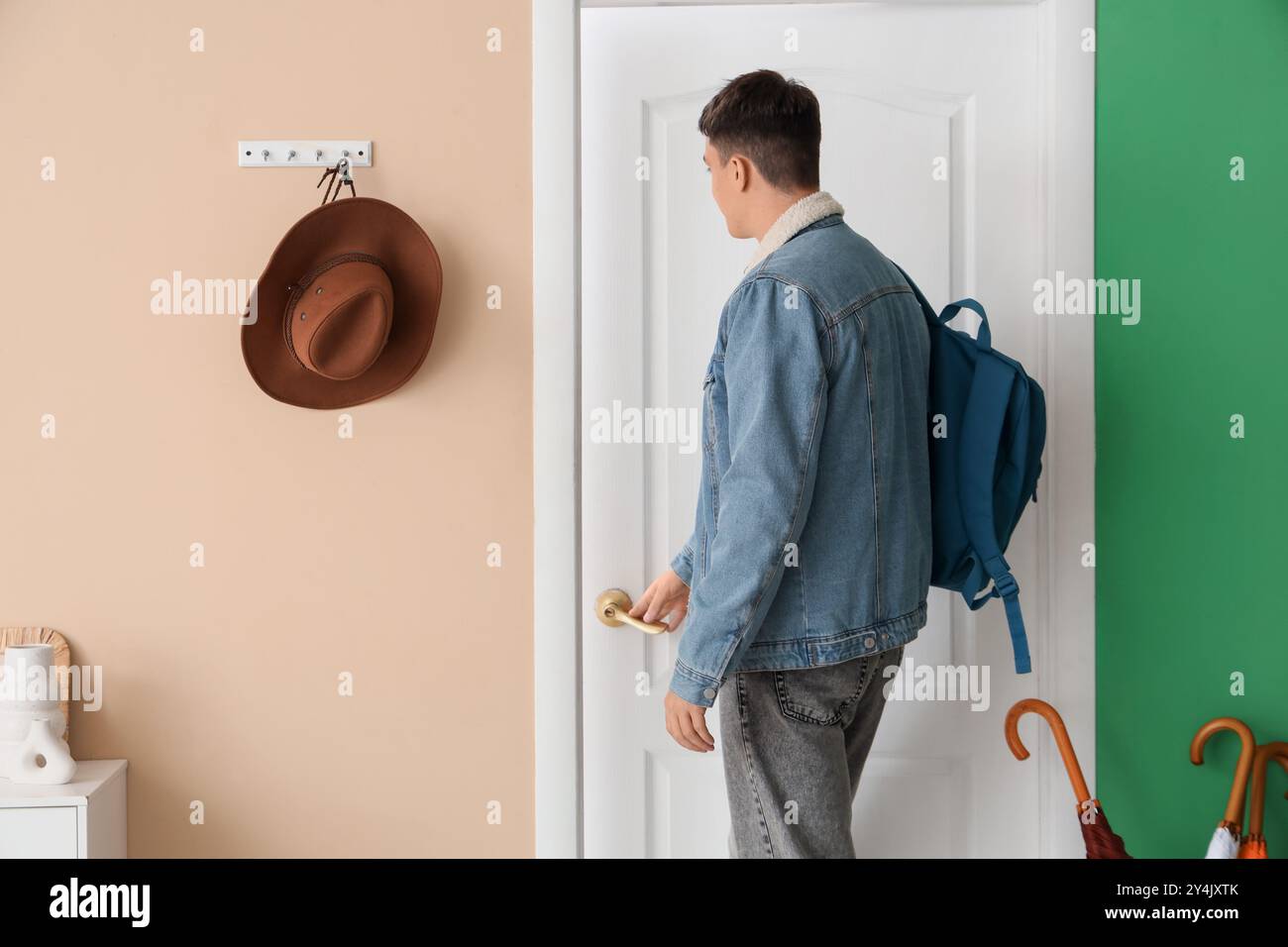 Young man with backpack opening door in hall, back view Stock Photo - Alamy