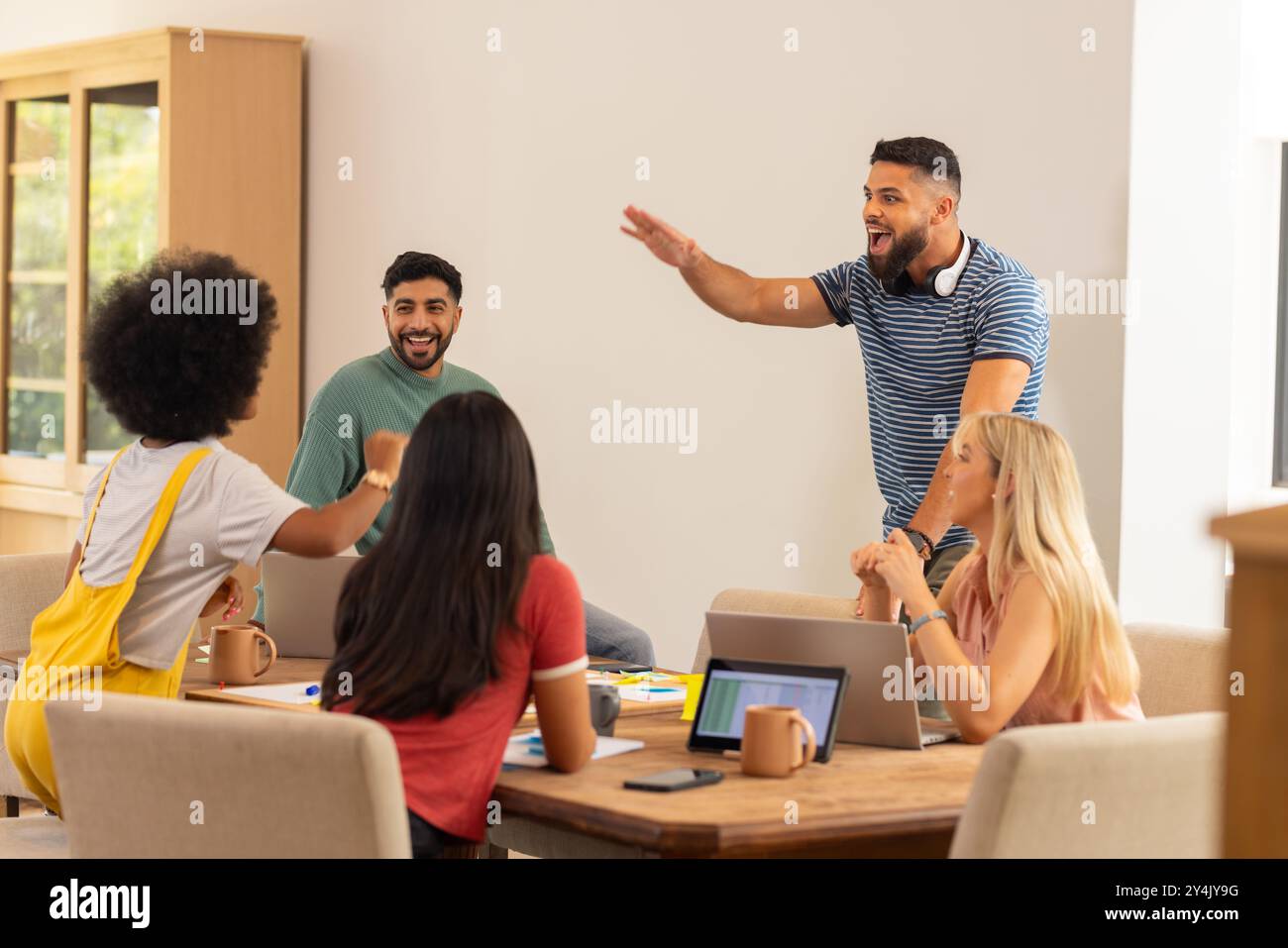 Group of young friends laughing and high-fiving while working on ...