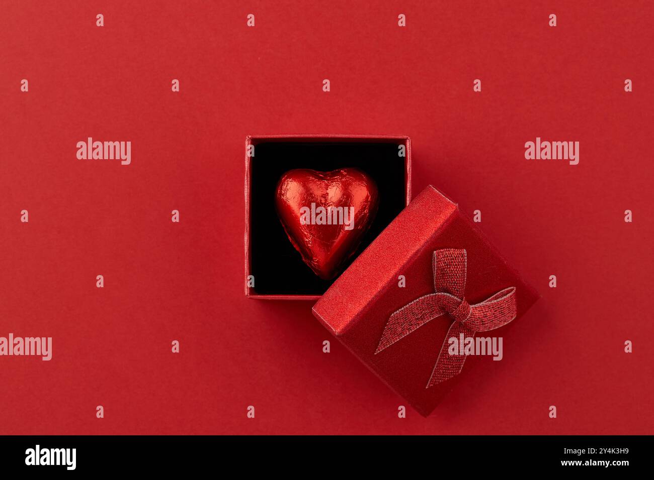 Heart shaped chocolate candy in red gift box on the red background ...