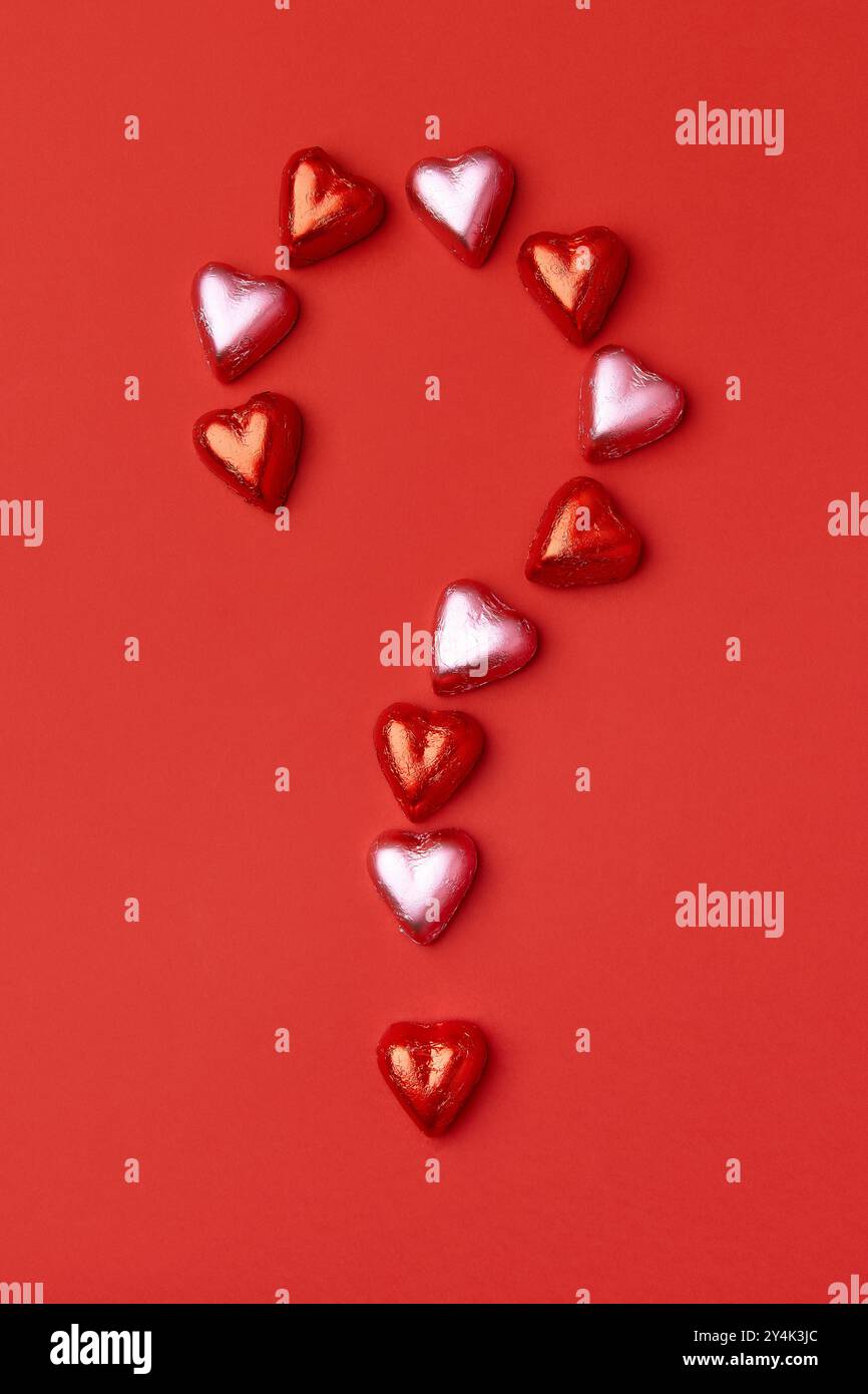 Question mark made of heart shaped chocolate candies on red background ...
