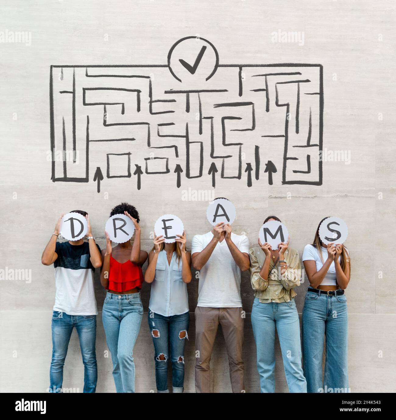 Diverse group of people holding letters spelling "DREAMS", with a maze ...
