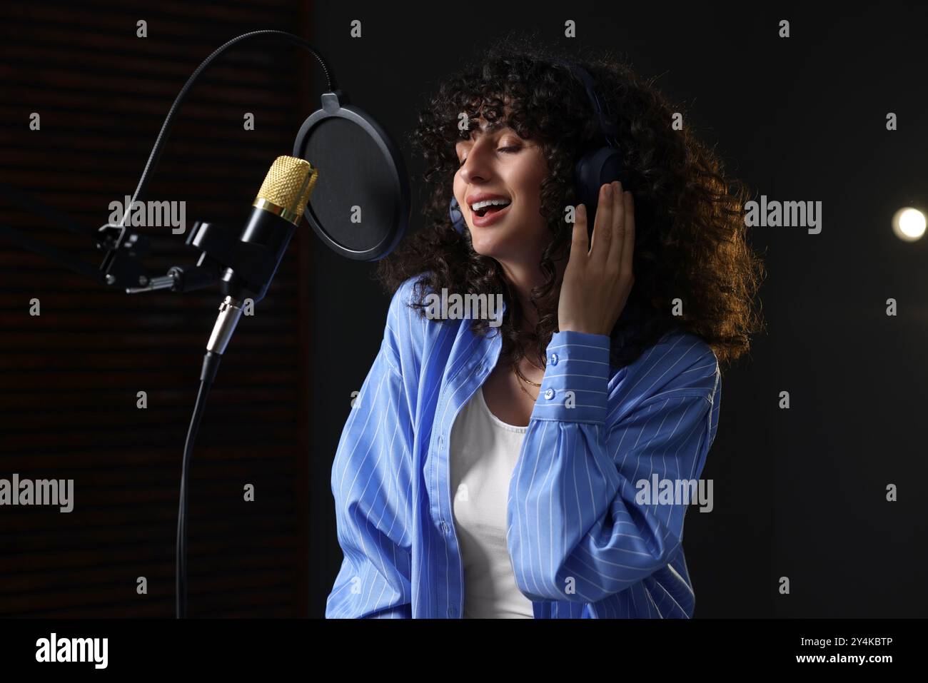 Vocalist with headphones singing into microphone in professional record ...