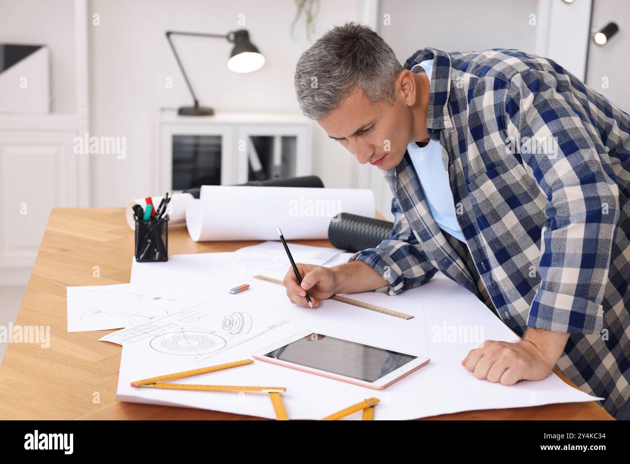 Architect making engineering drawing at wooden table in office Stock ...