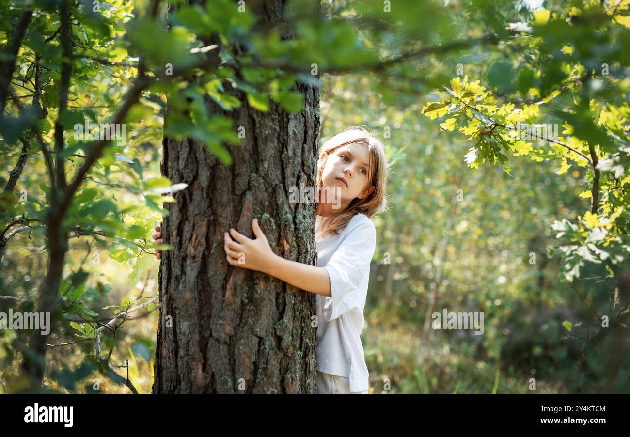 A teenage girl hugs a tree in the forest. Hugging and touching trees to ...