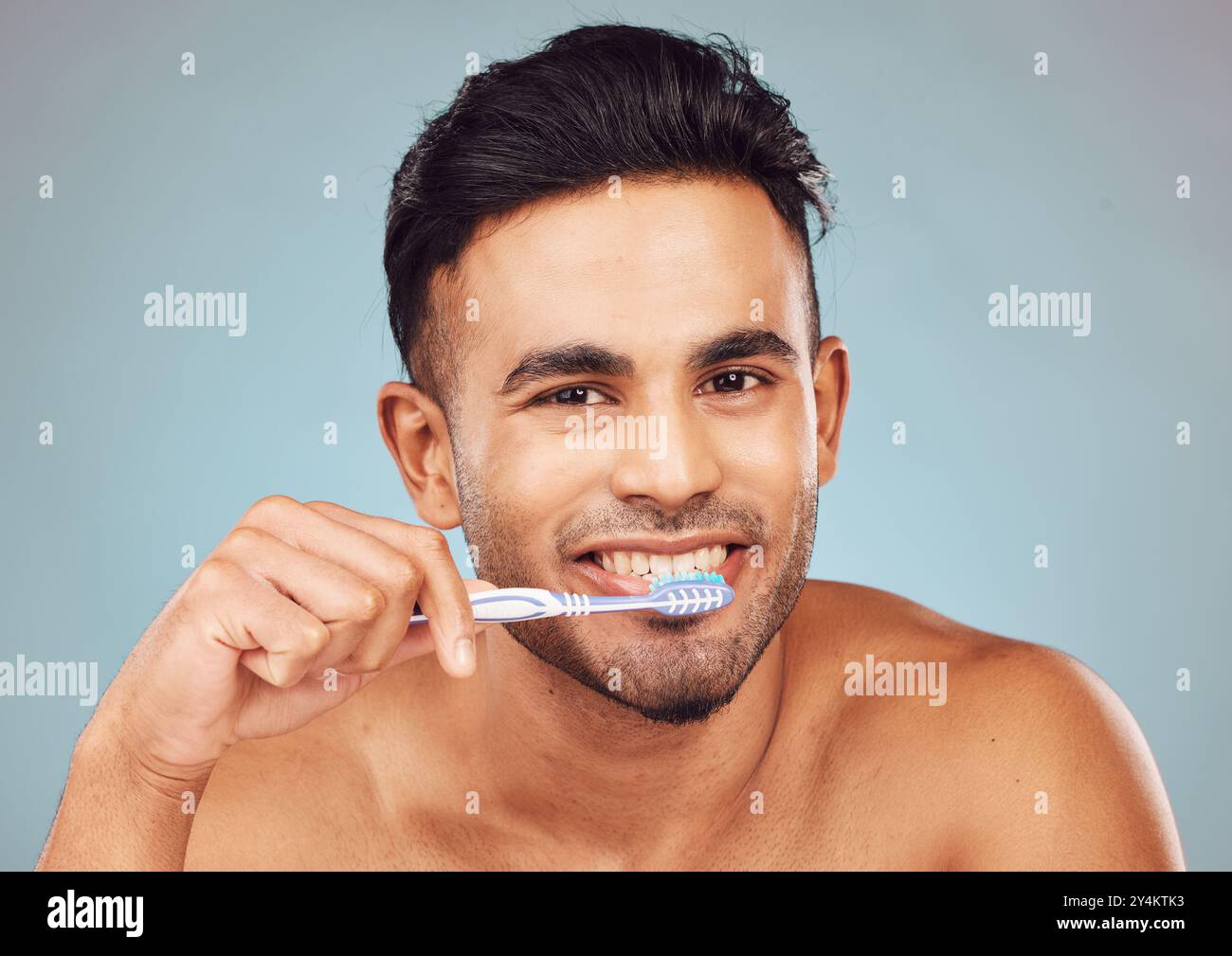 Man, brushing teeth and happy in studio portrait for self care, hygiene or oral wellness by blue ...
