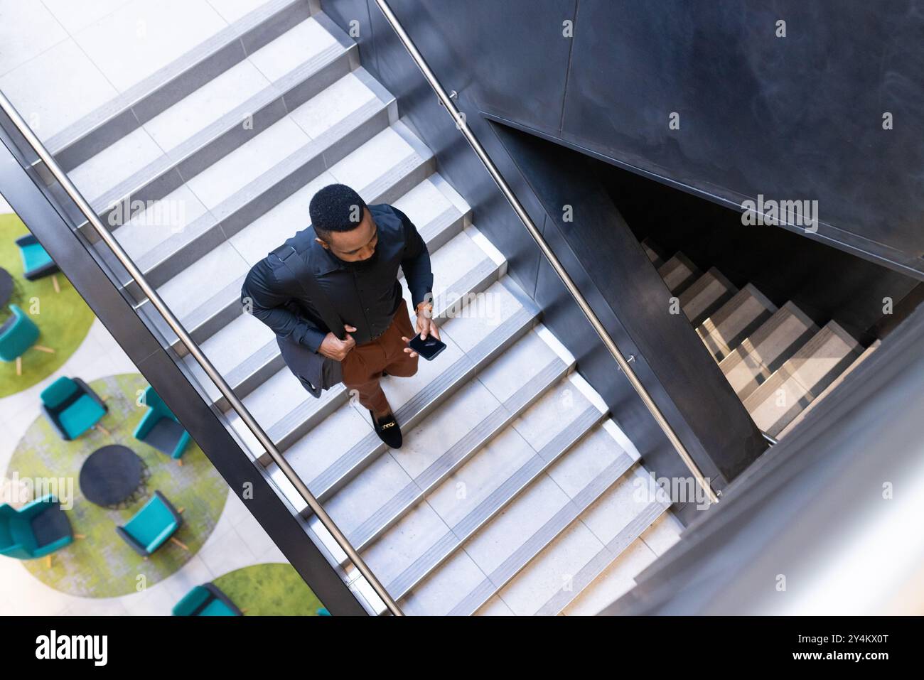 Walking up stairs, businessman holding smartphone and coffee cup in ...