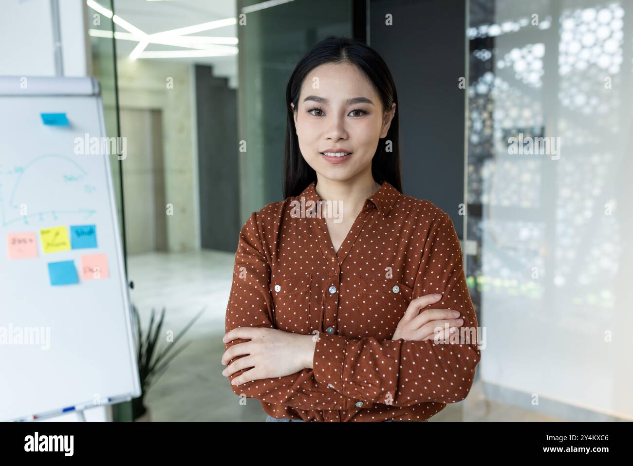 Confident asian businesswoman standing with arms crossed in modern ...
