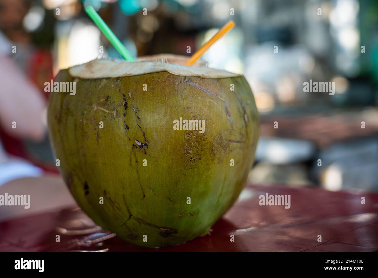 Coconut with two straws ready to drink Stock Photo - Alamy
