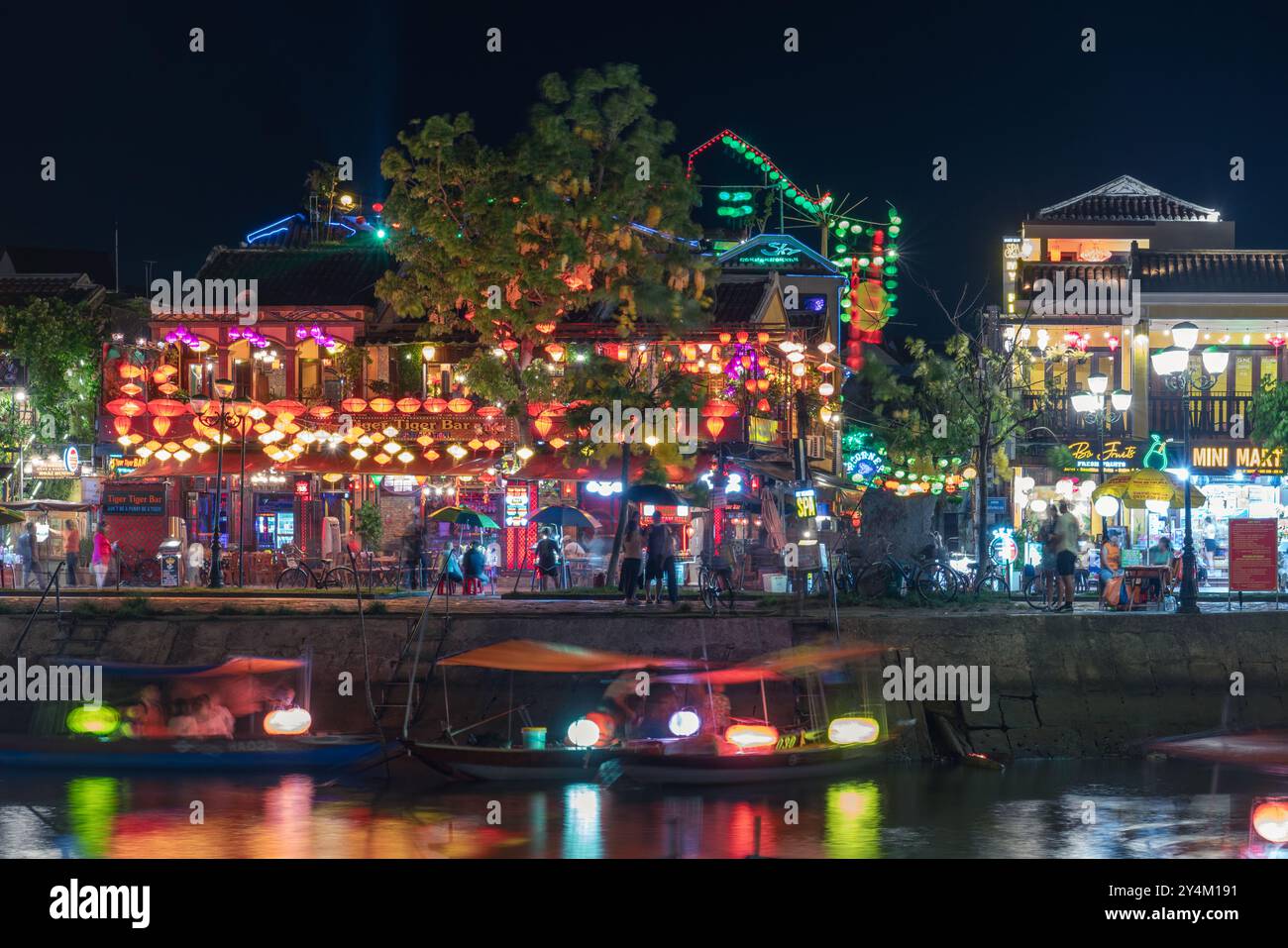 Colorful riverside buildings with traditional lanterns and boats in the center of Hoi An, a ...