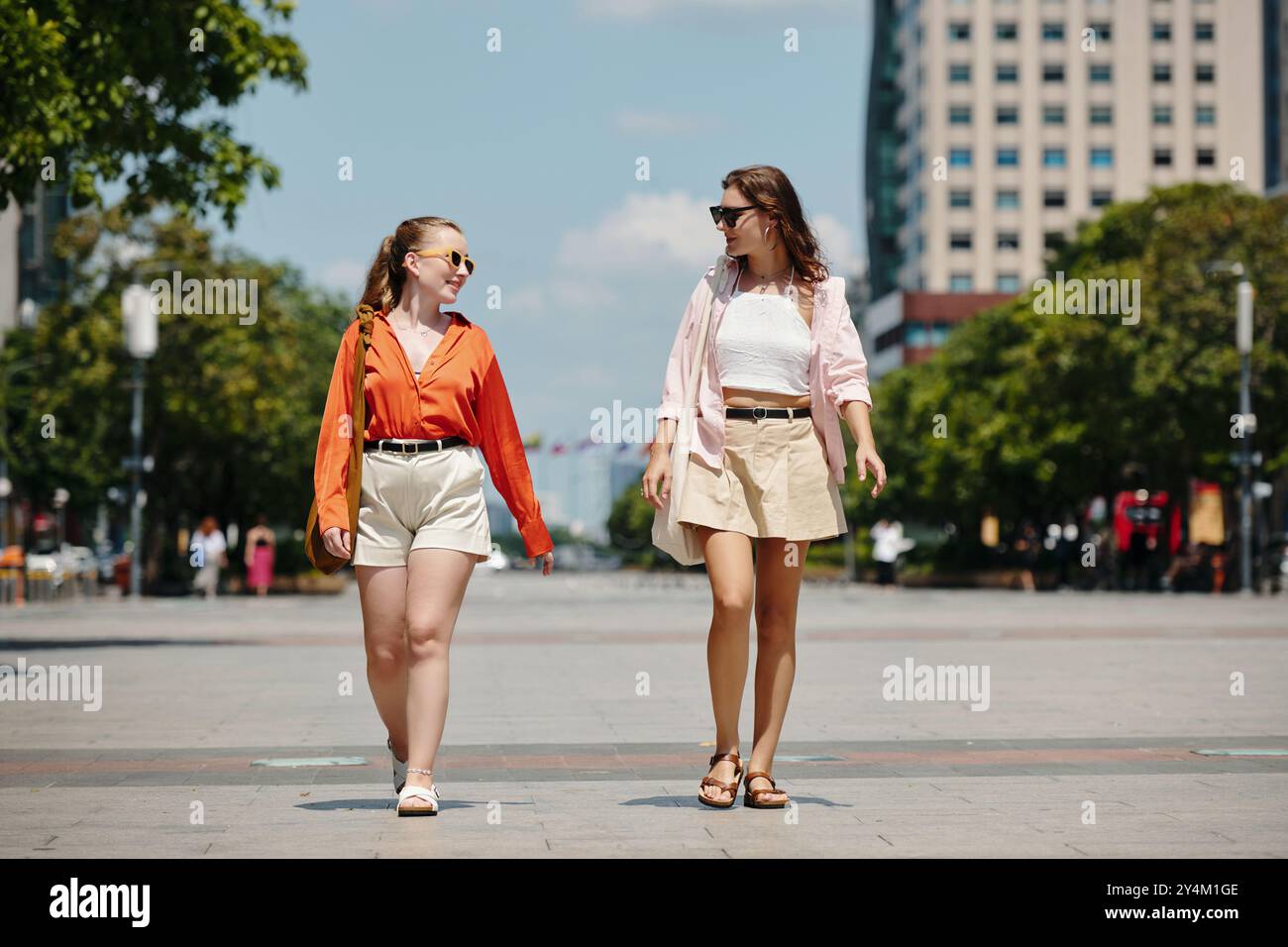 Two Women Walking Down City Street in Daylight Stock Photo - Alamy
