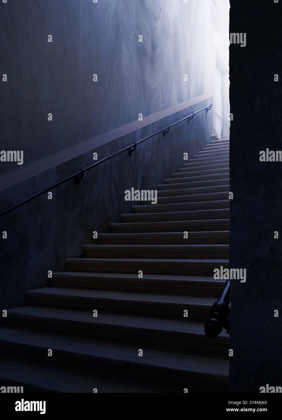 Conceptual view from below of a long staircase with a bright light at ...