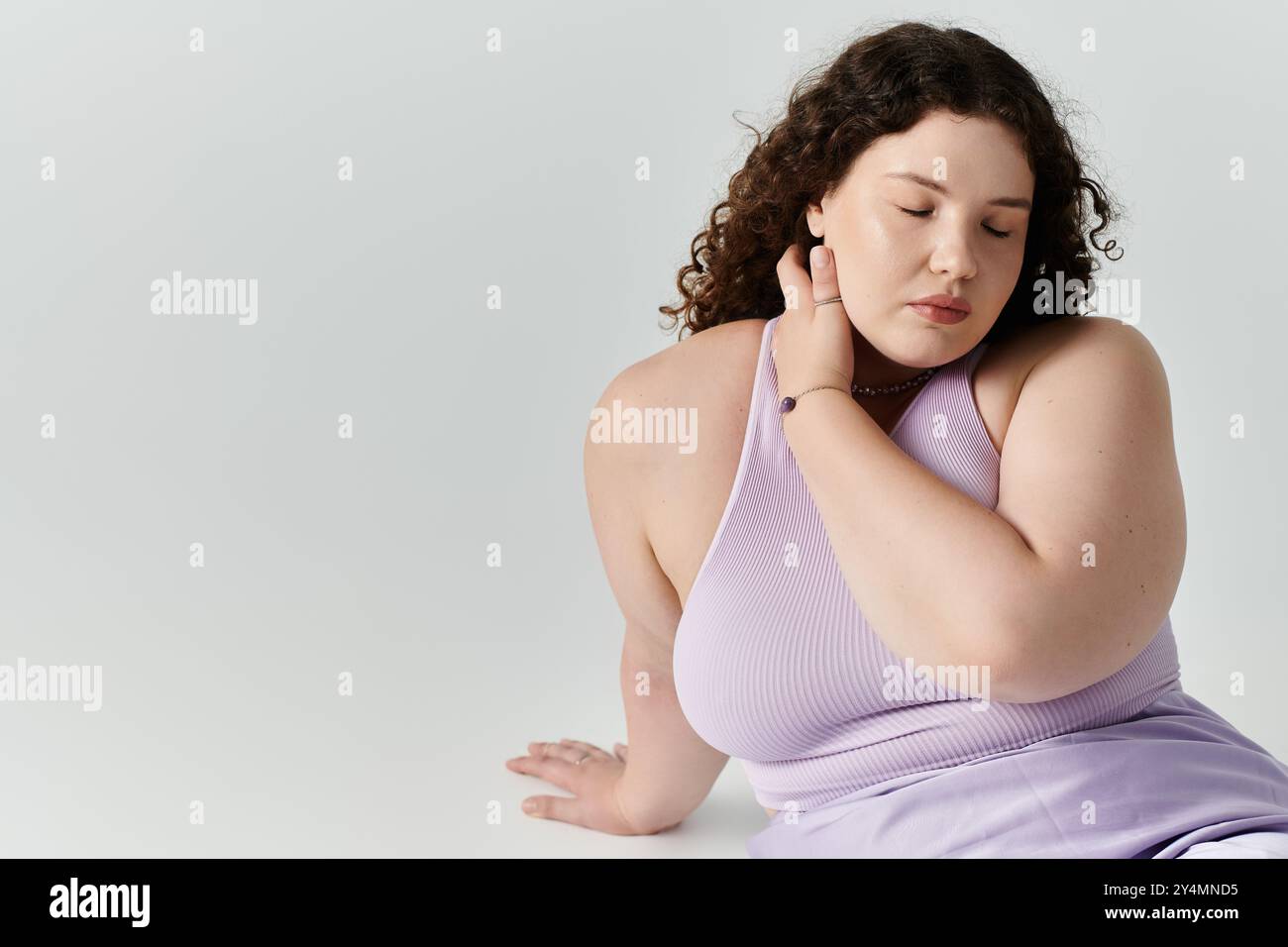 A beautiful plus size woman gracefully poses while gently touching her ...