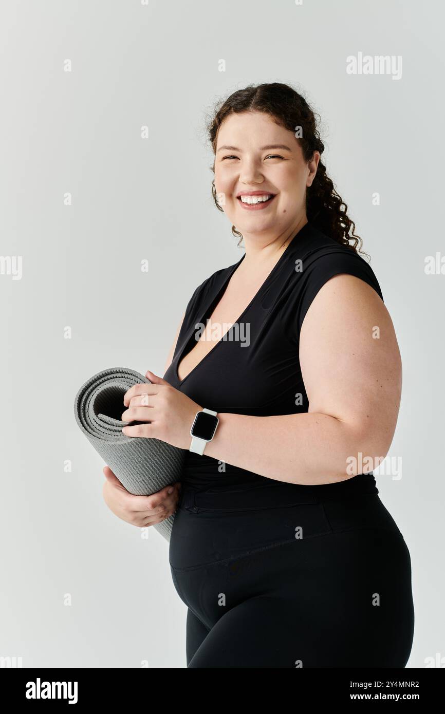 A joyful plus size woman beams while holding her yoga mat, exuding ...