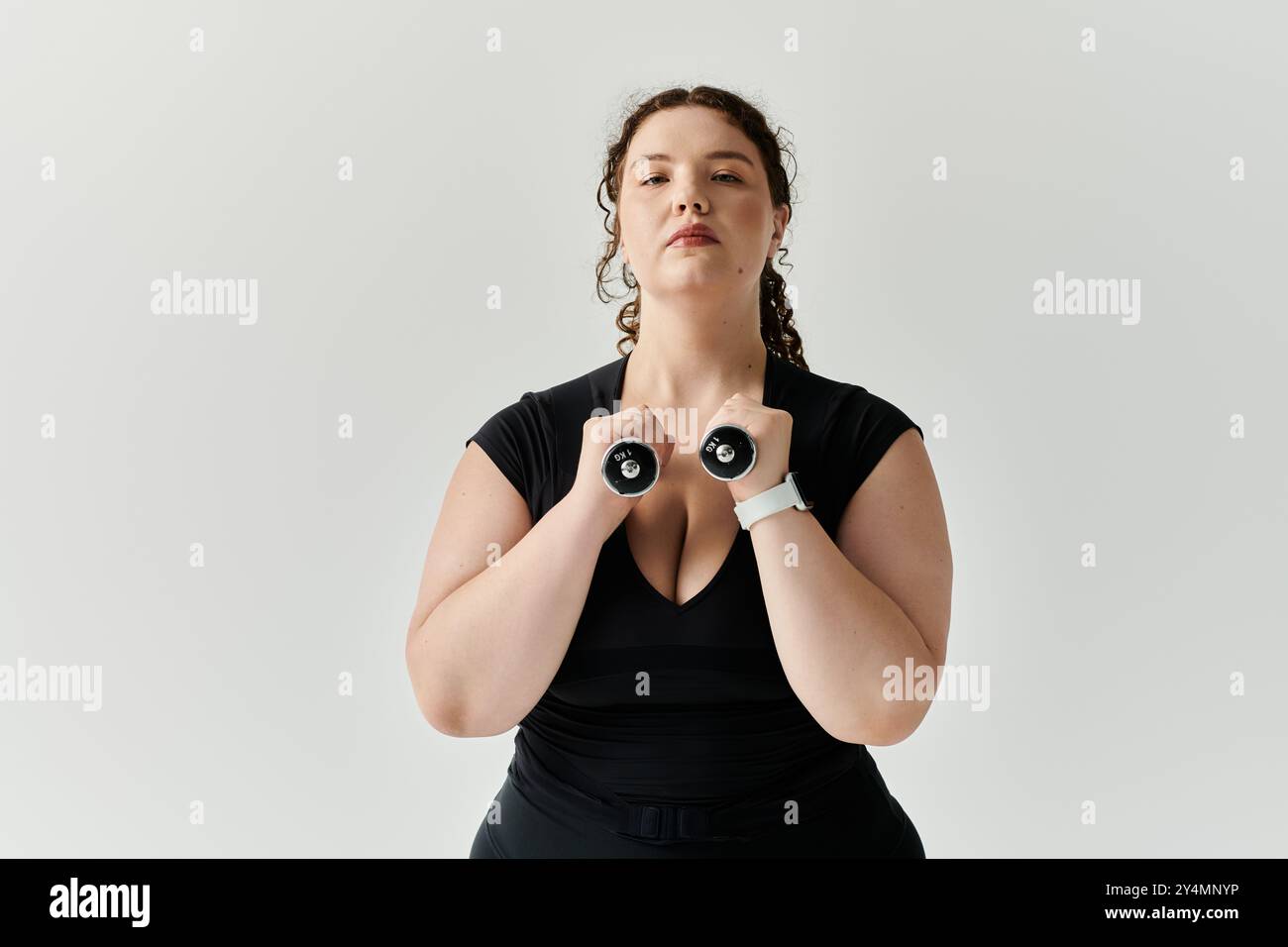 A beautiful plus size woman is engaged in strength training, showcasing ...