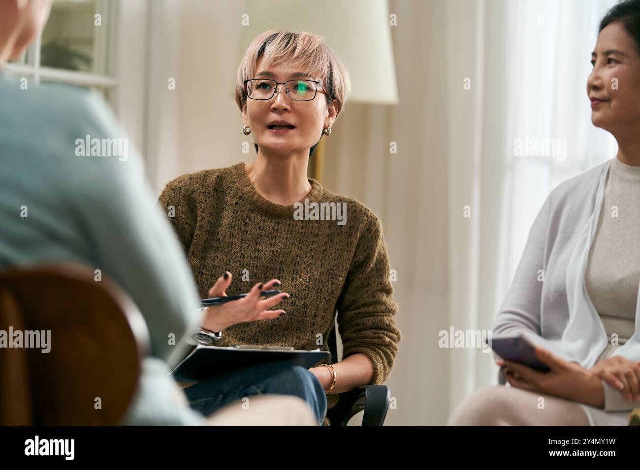 asian female counselor leading a discussion session for a group of ...