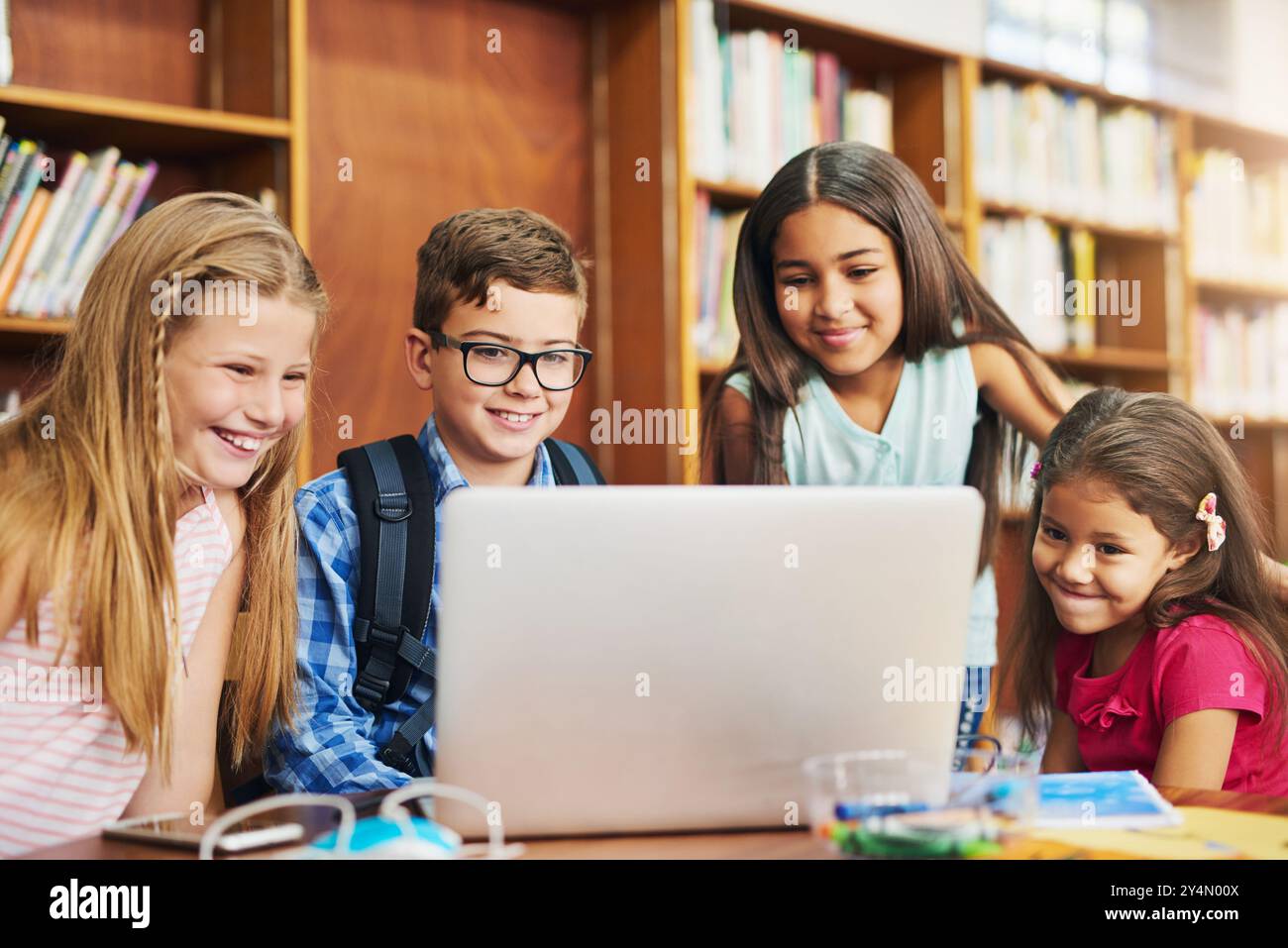 Happy children, students or elearning with laptop at library for ebook ...