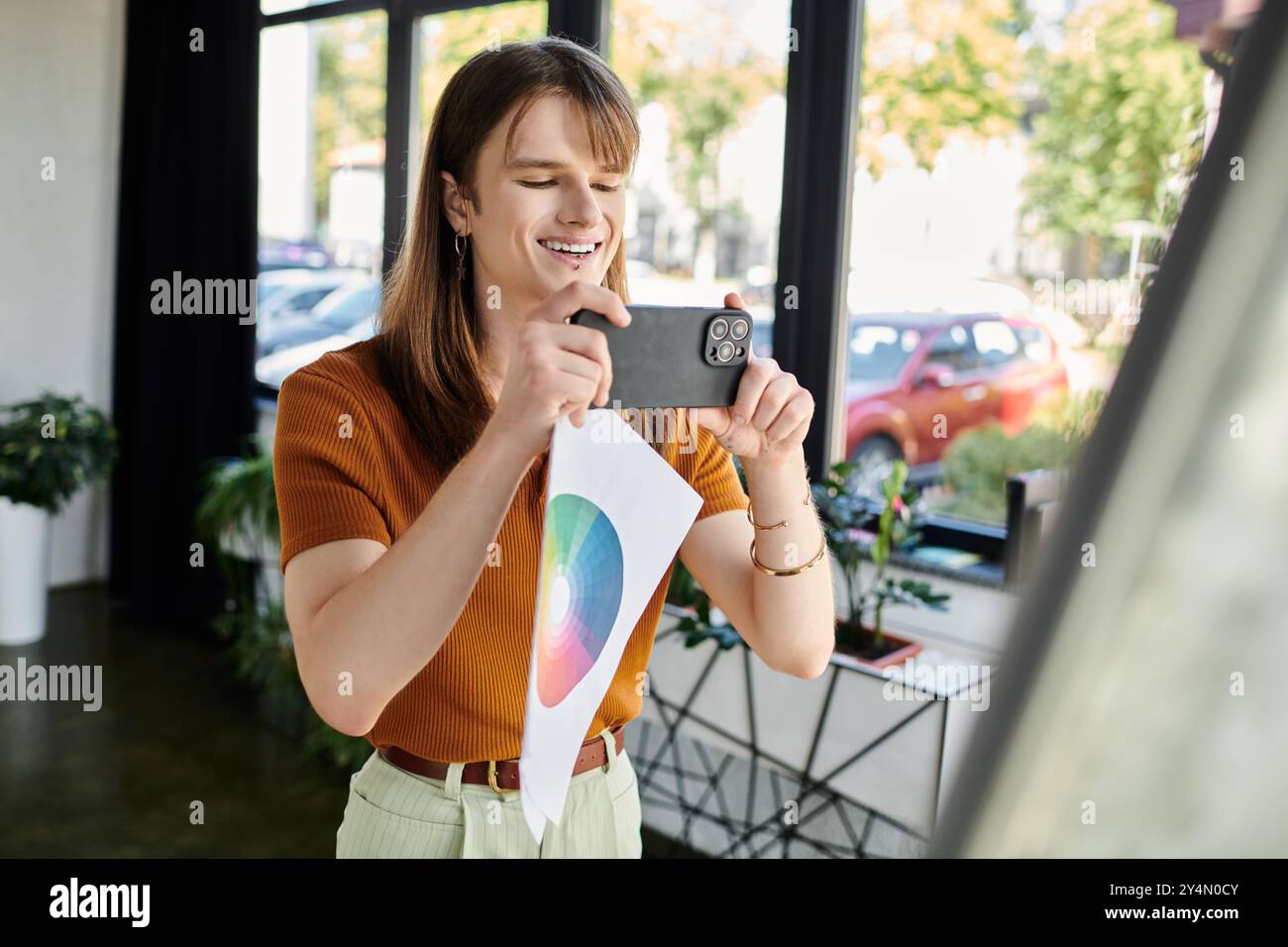 A non binary person enthusiastically takes photos of design concepts in ...