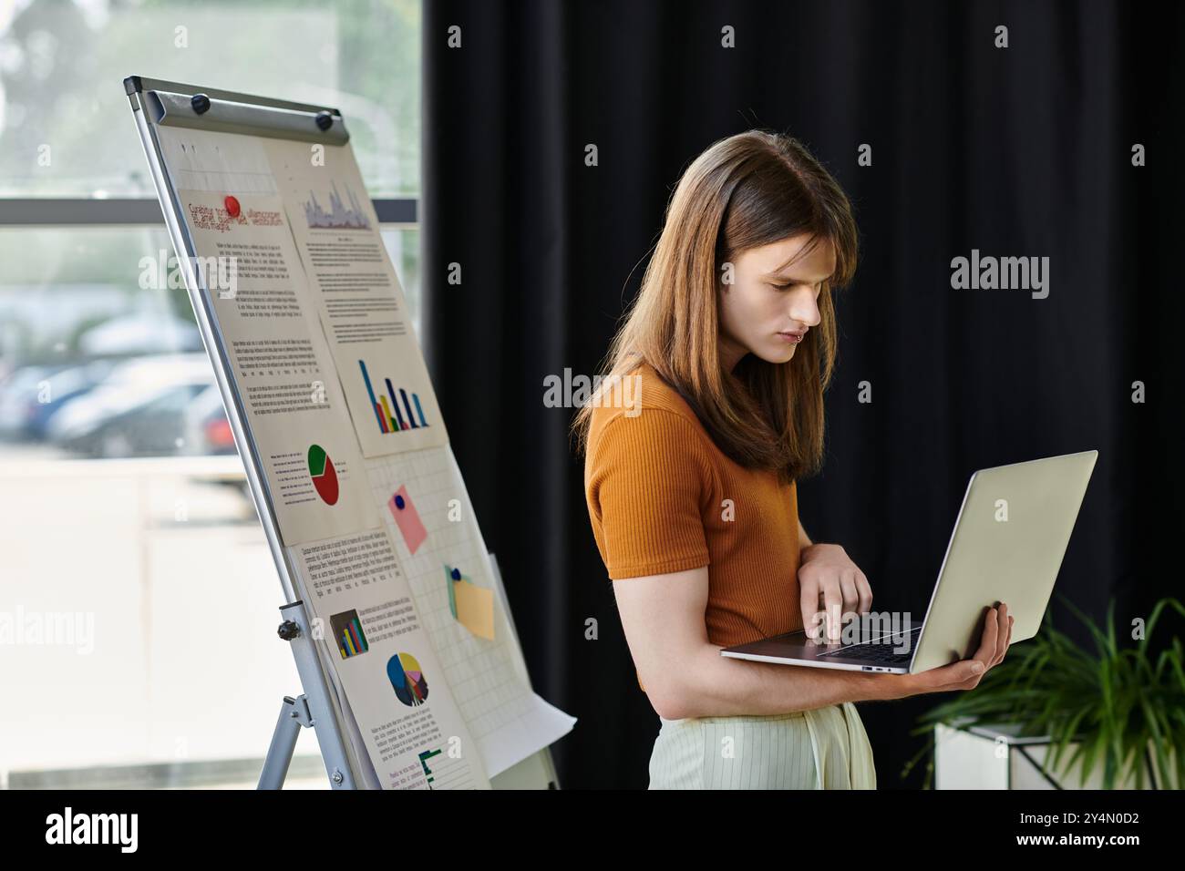 The individual focuses intently on their laptop while surrounded by ...