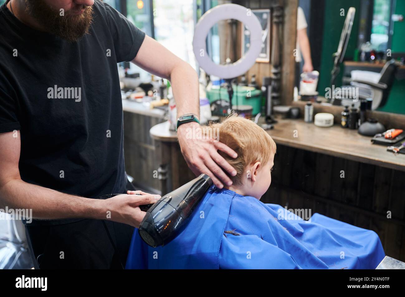 Back view of professional barber styling little boy's hair. Male ...