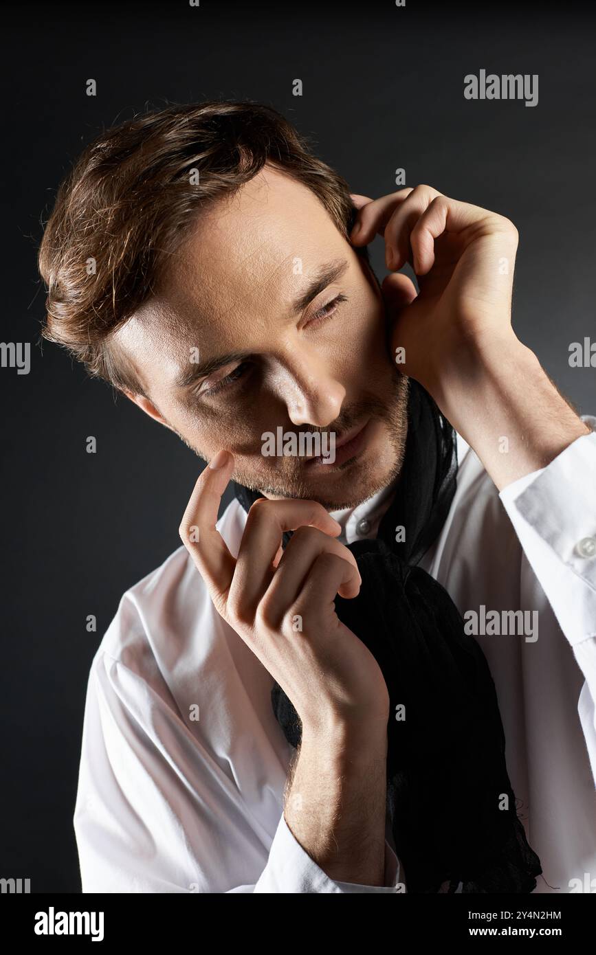 A handsome man dressed in crisp attire gently adjusts his scarf ...