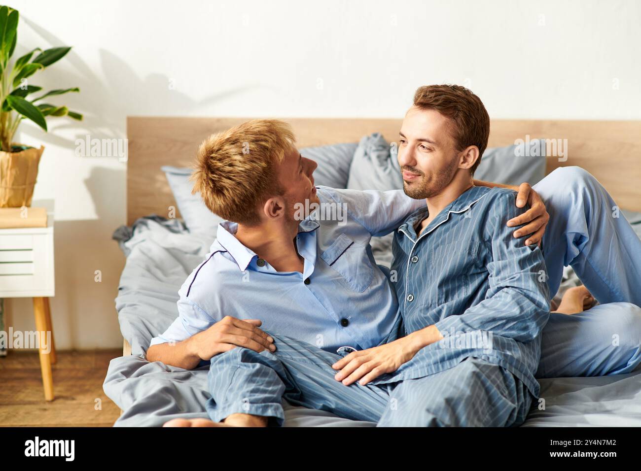 A loving gay couple in pajamas shares a tender morning moment ...
