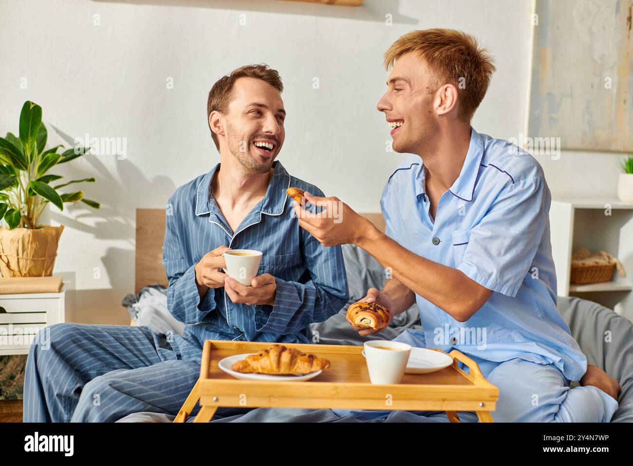 A loving gay couple enjoys a cozy morning together, sipping coffee and ...