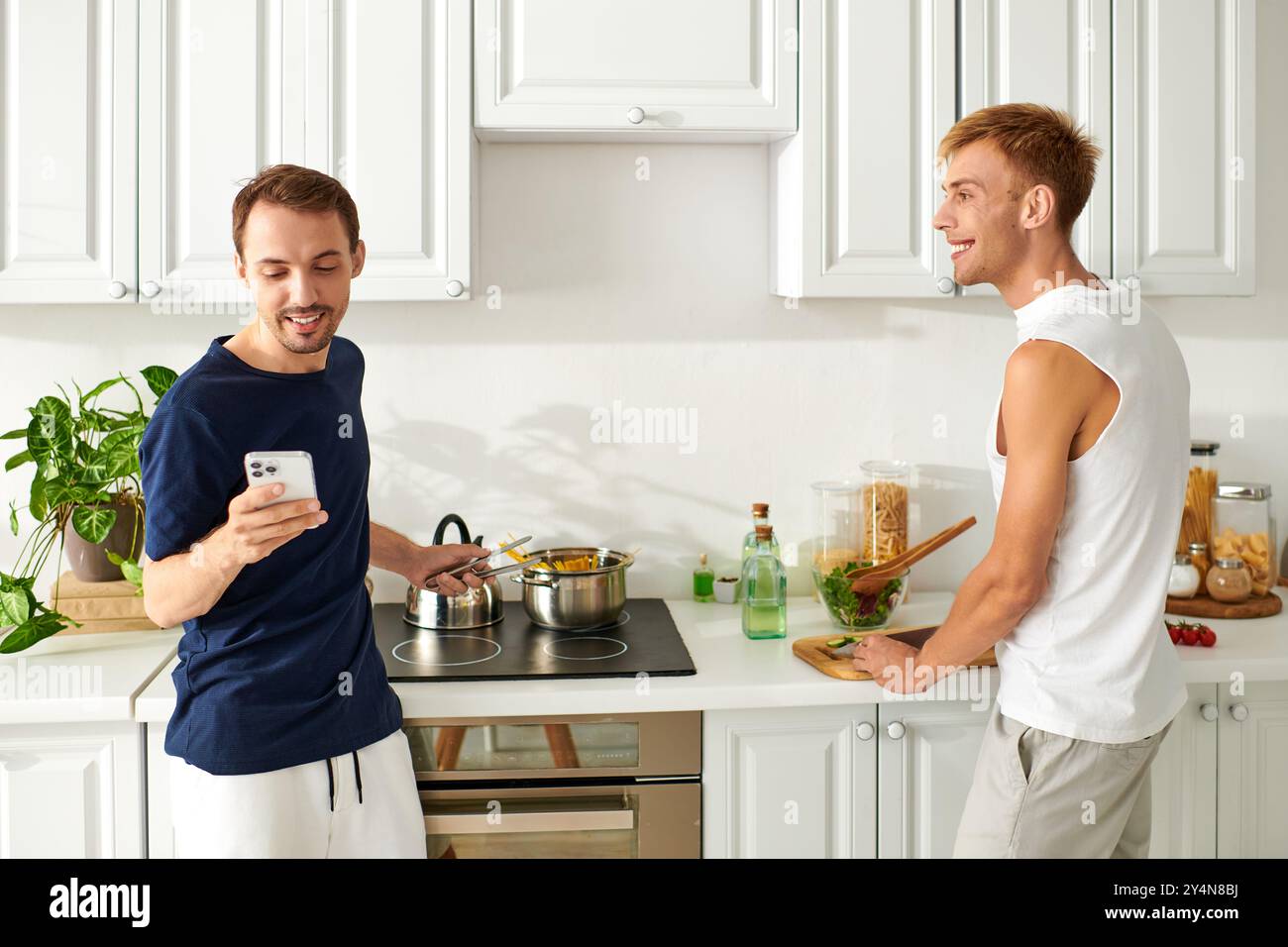 Two men cheerfully cooking together in a modern kitchen, embracing ...