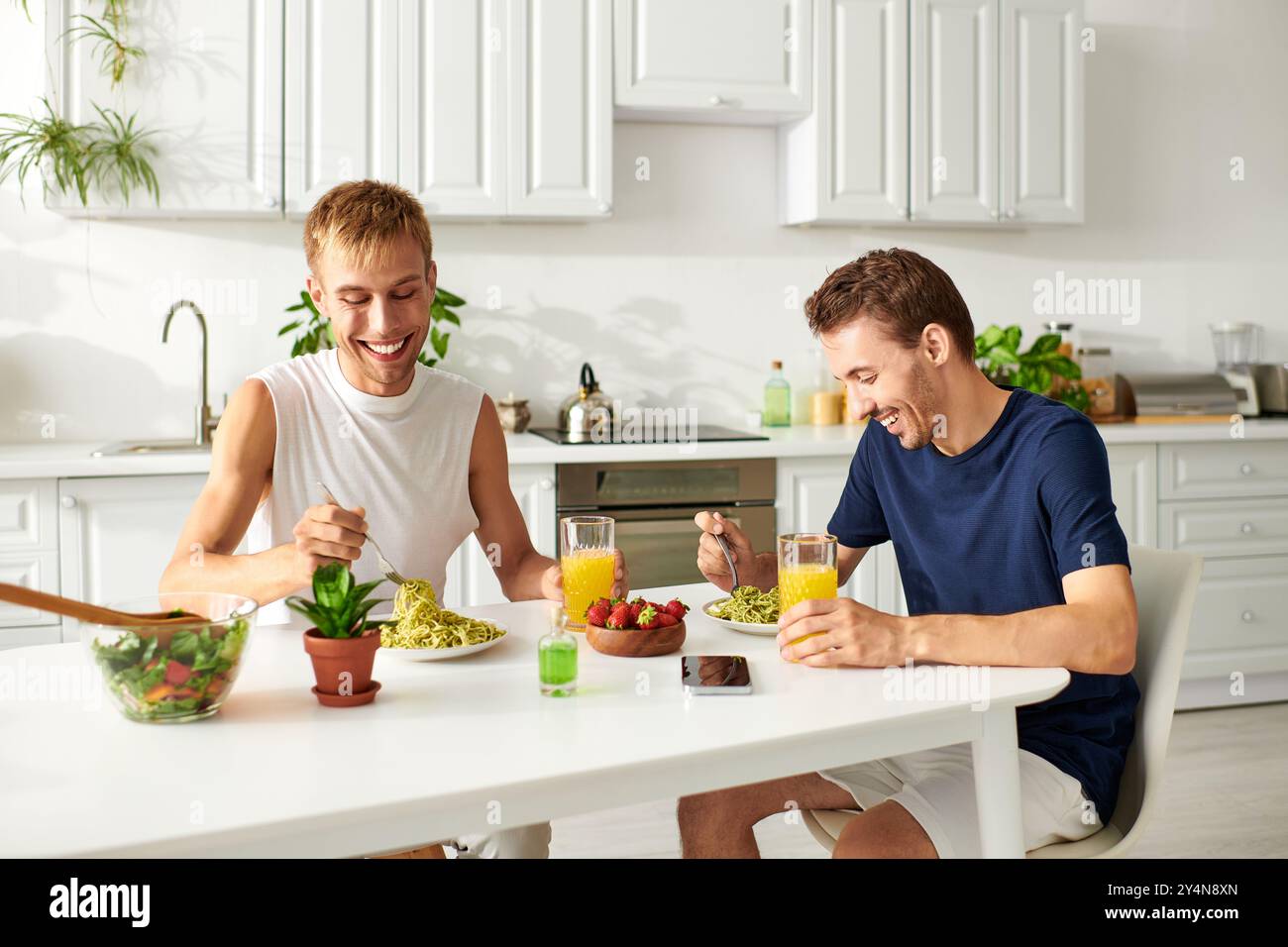 Two men share a delightful moment in a stylish kitchen while eating ...