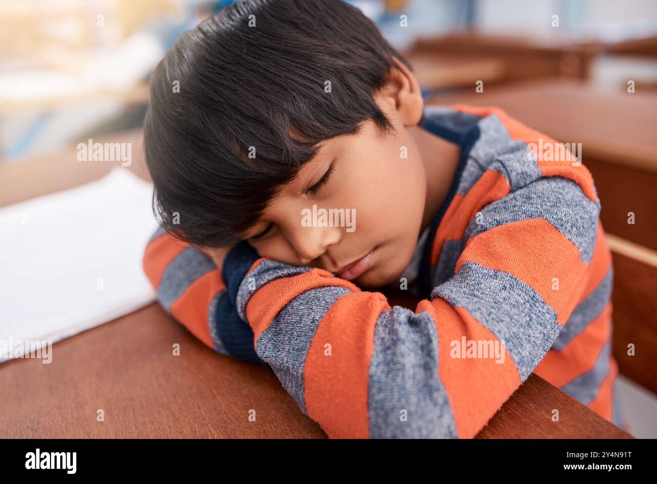 School, sleeping and tired with boy student in classroom for child development or learning ...