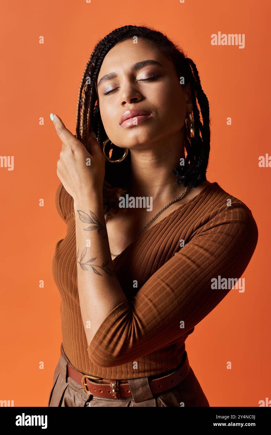 A young African American woman with braided hair strikes a stylish pose ...