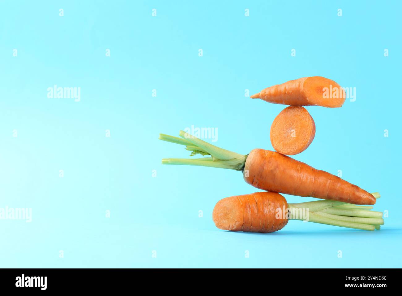 Whole and cut fresh carrots on light blue background, space for text ...