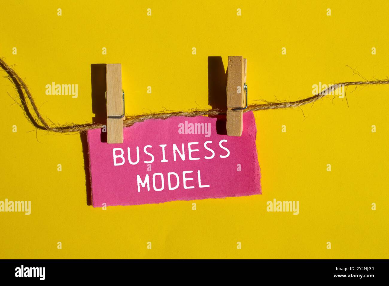 Business model message written on ripped pink paper piece with yellow background. Conceptual ...