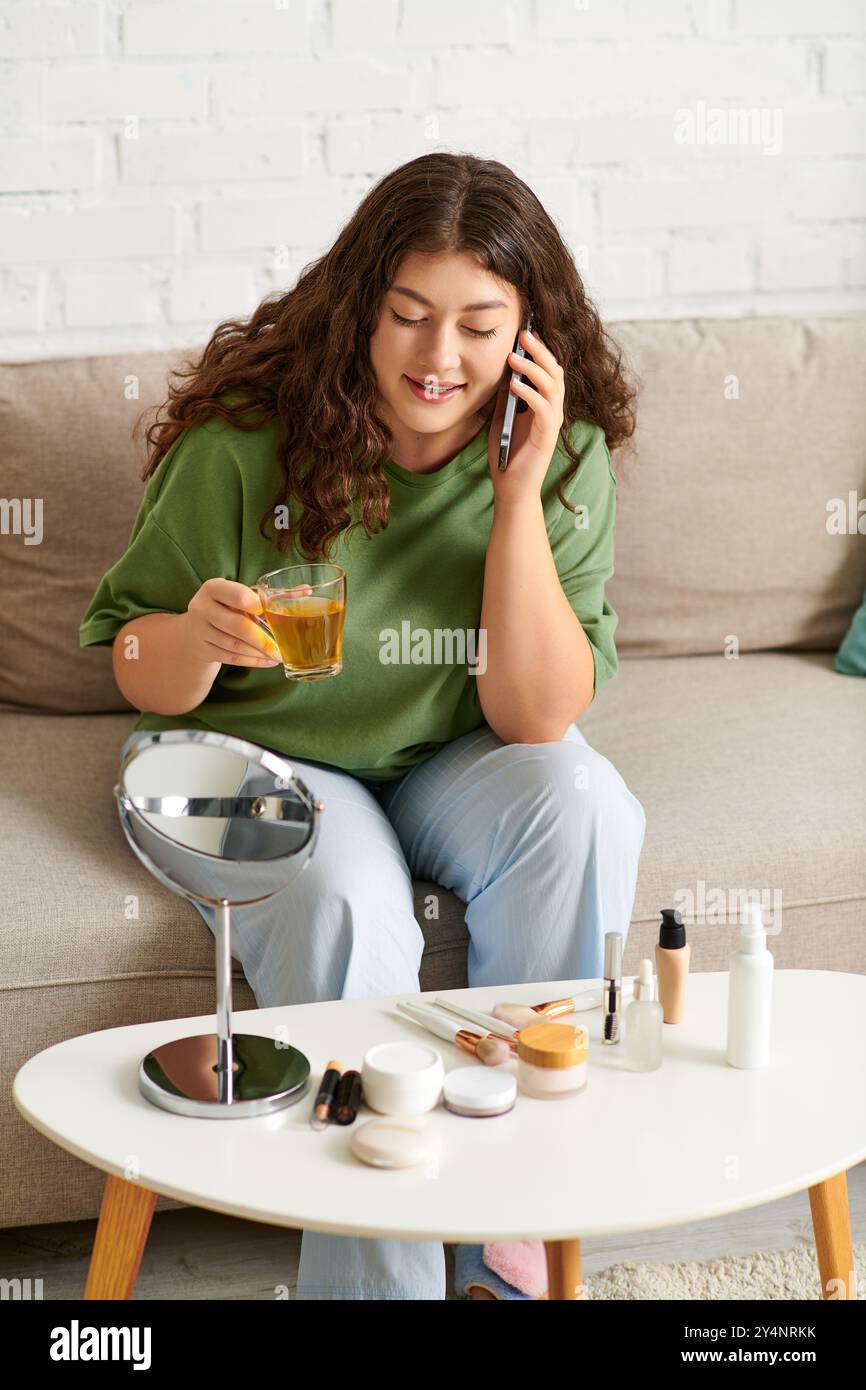 A curly-haired woman relaxes in comfortable attire, sipping tea and ...
