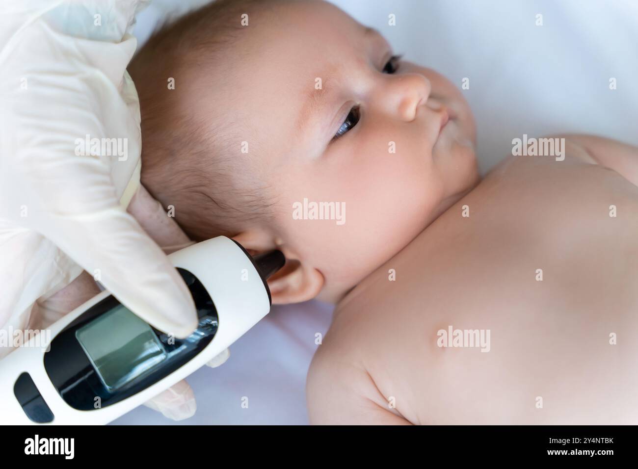 Female pediatrician with digital infrared thermometer measuring baby ...