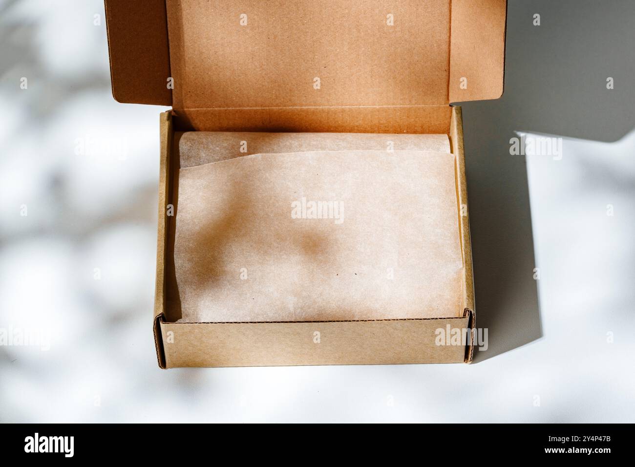 A small, empty cardboard box with unwrapped parchment resting inside on ...