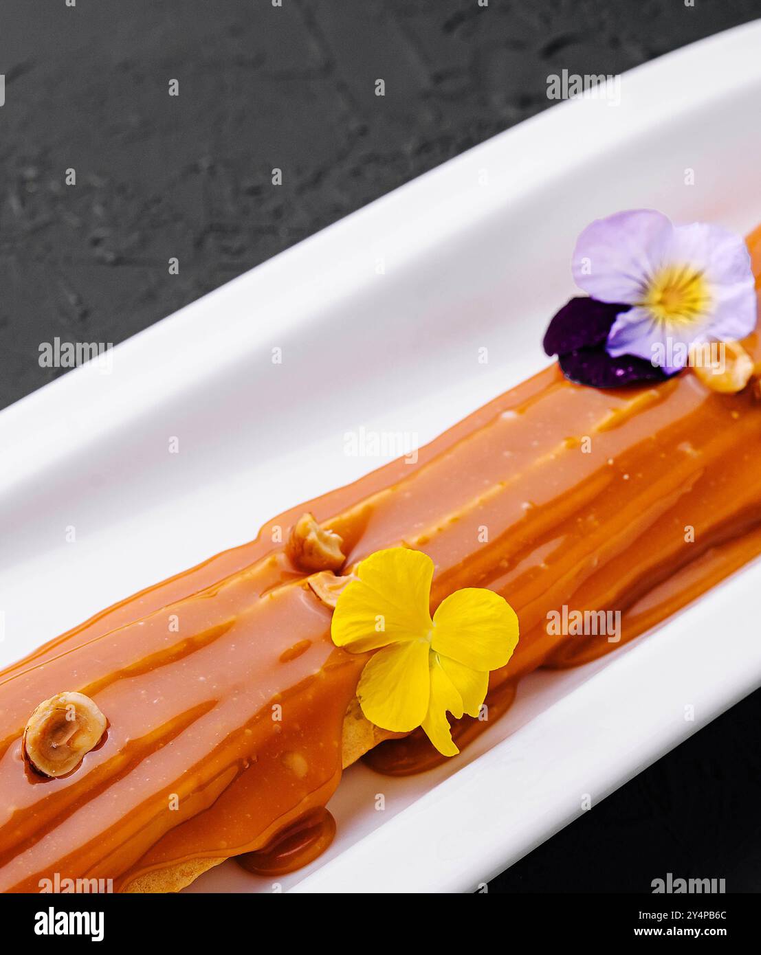 caramel French eclair pastry on white rectangle plate Stock Photo - Alamy