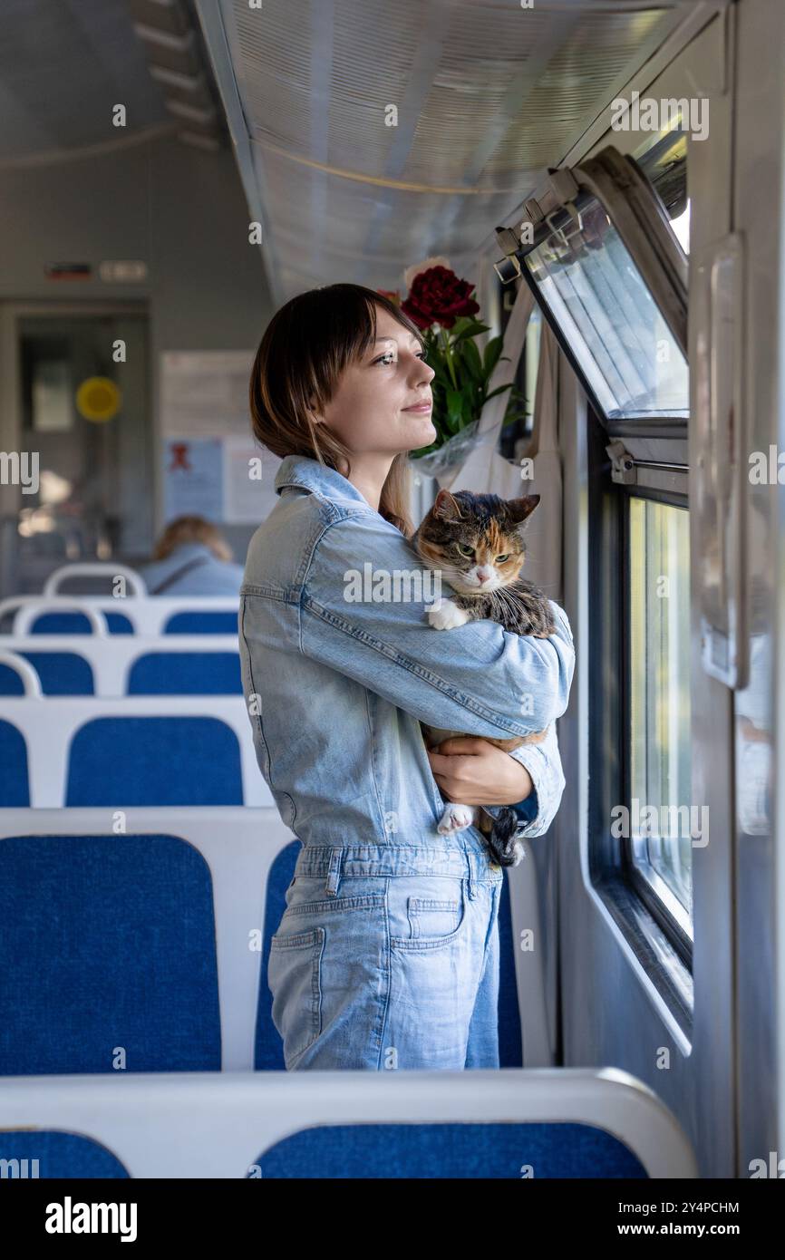 Cat traveling by train with owner. Woman cuddles her cat, soothing it ...