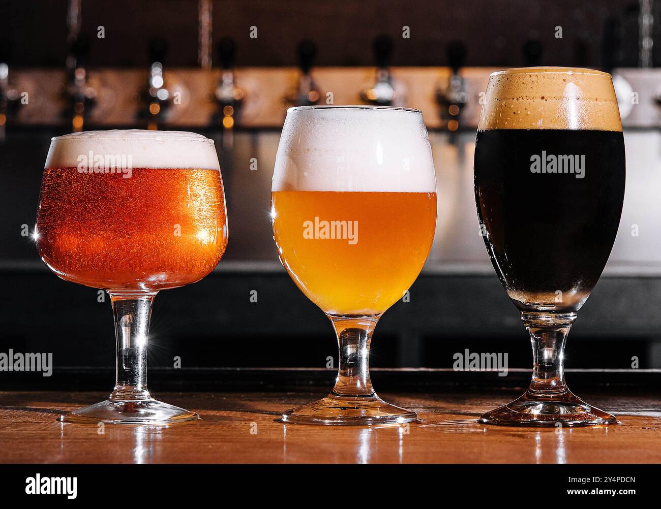 different types of craft beer in glasses on table in pub interior in ...