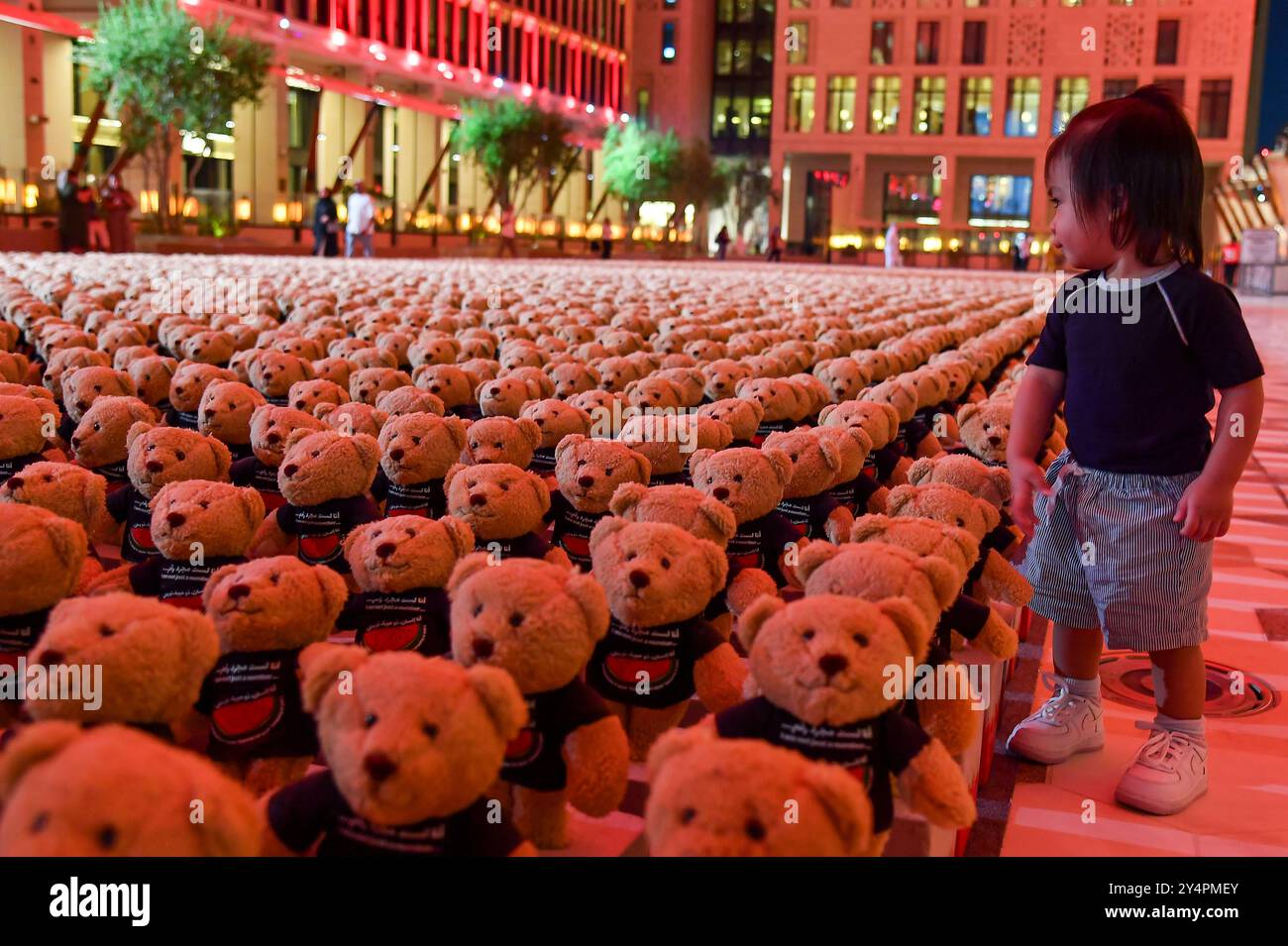 A young child looks at an installation of teddy bears titled ''Echo of ...