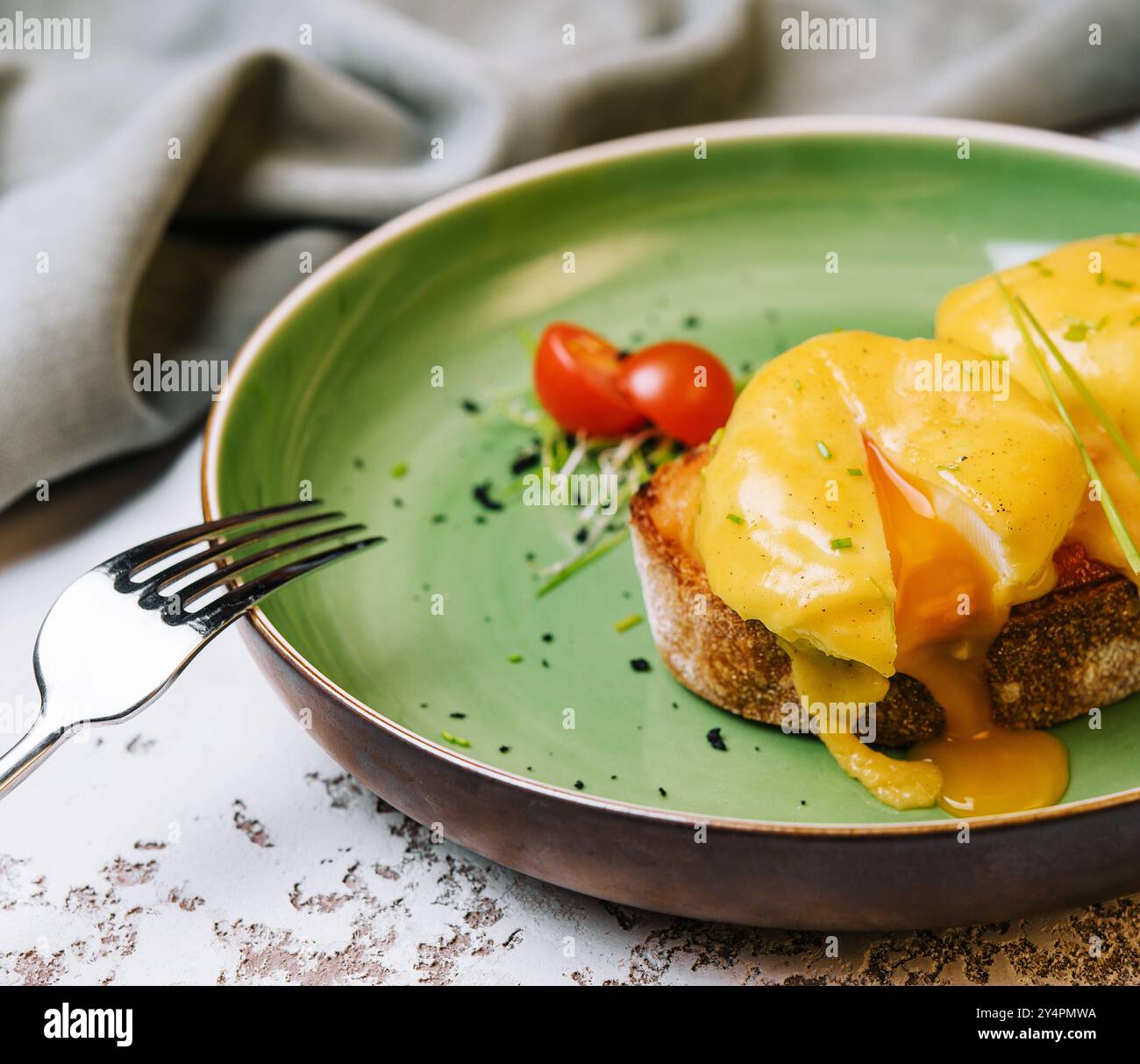 Classic egg benedict on green plate Stock Photo - Alamy