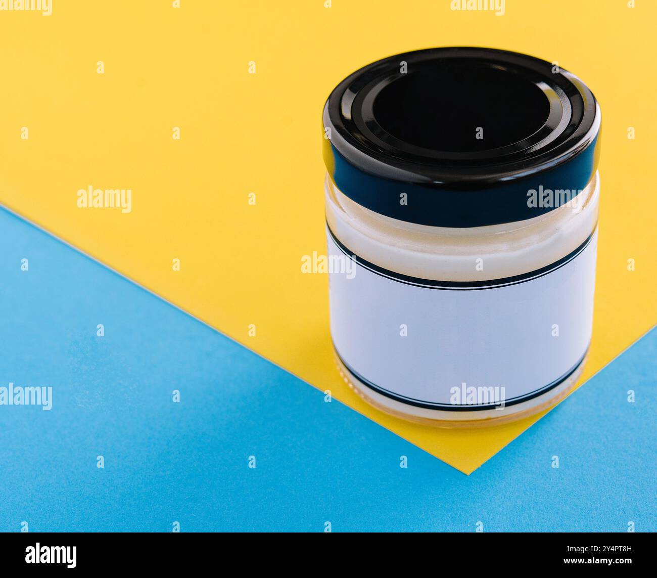 Glass mayonnaise jar with black lid on yellow Stock Photo - Alamy