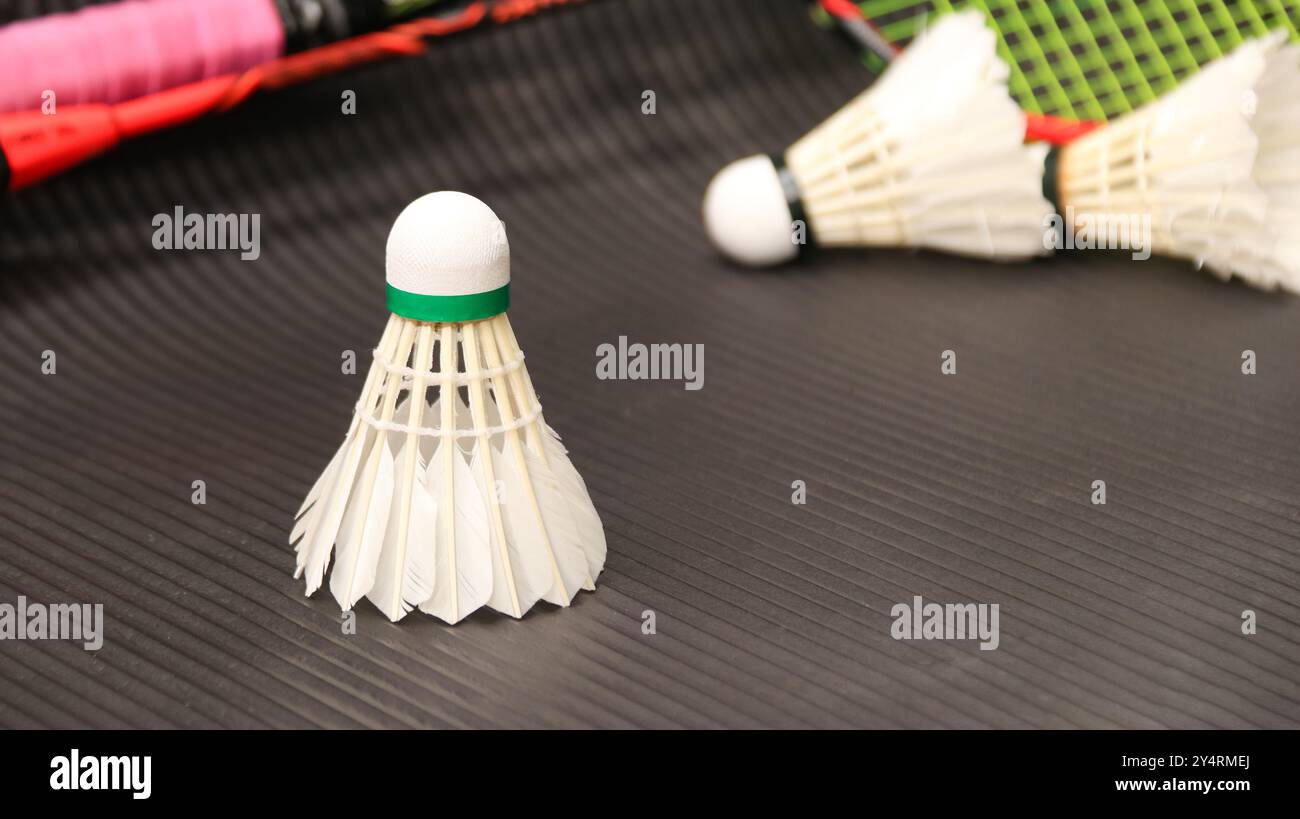 White badminton shuttlecocks and badminton rackets on dark background ...