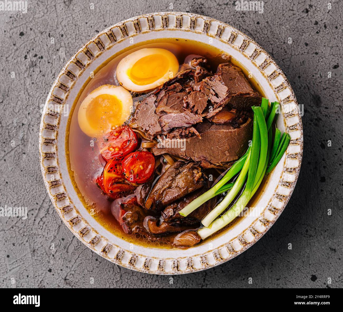 Traditional beef ramen with soft-boiled egg, tomatoes, and green onions ...