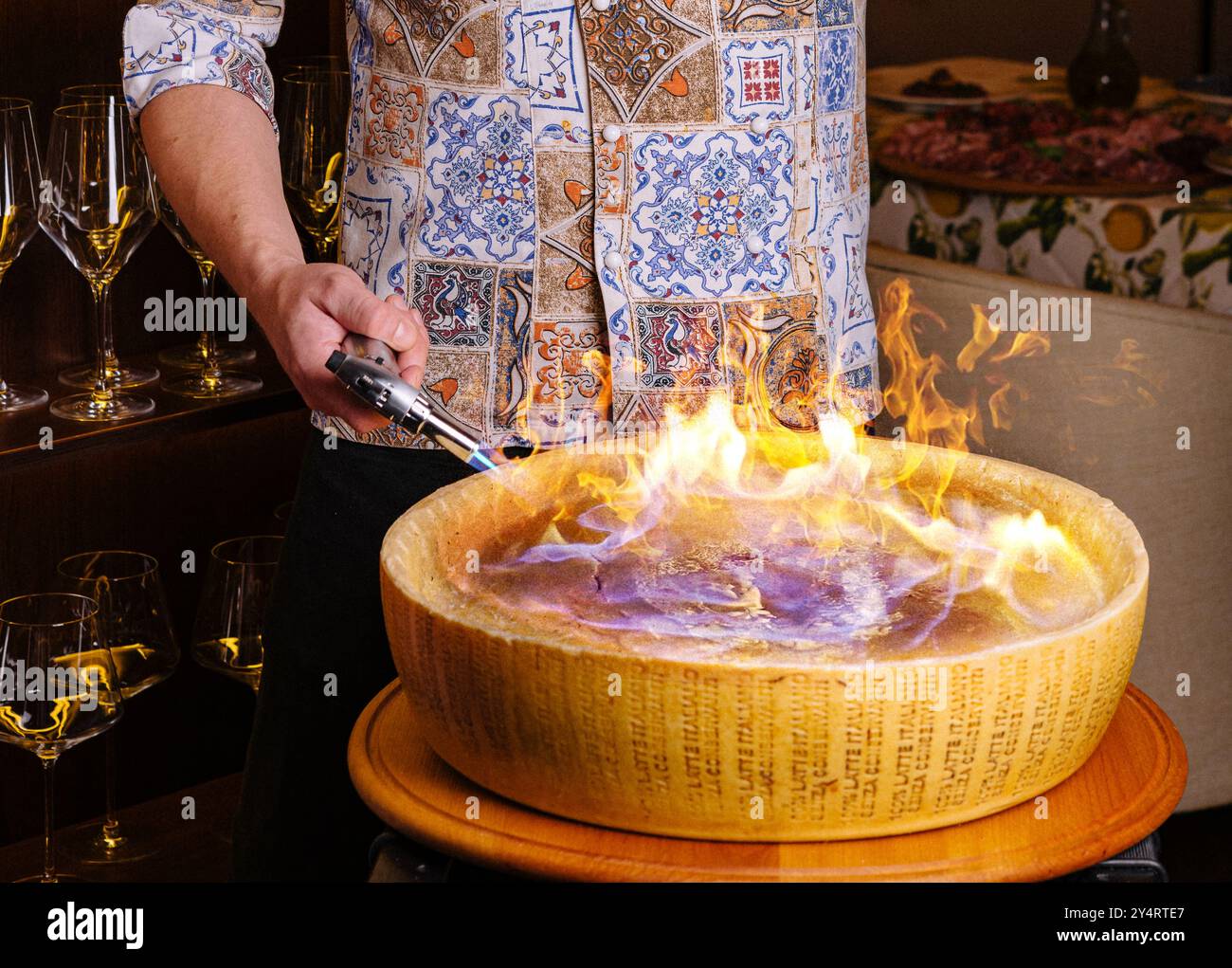 Chef preparing pasta in a flaming cheese wheel at a gourmet restaurant ...
