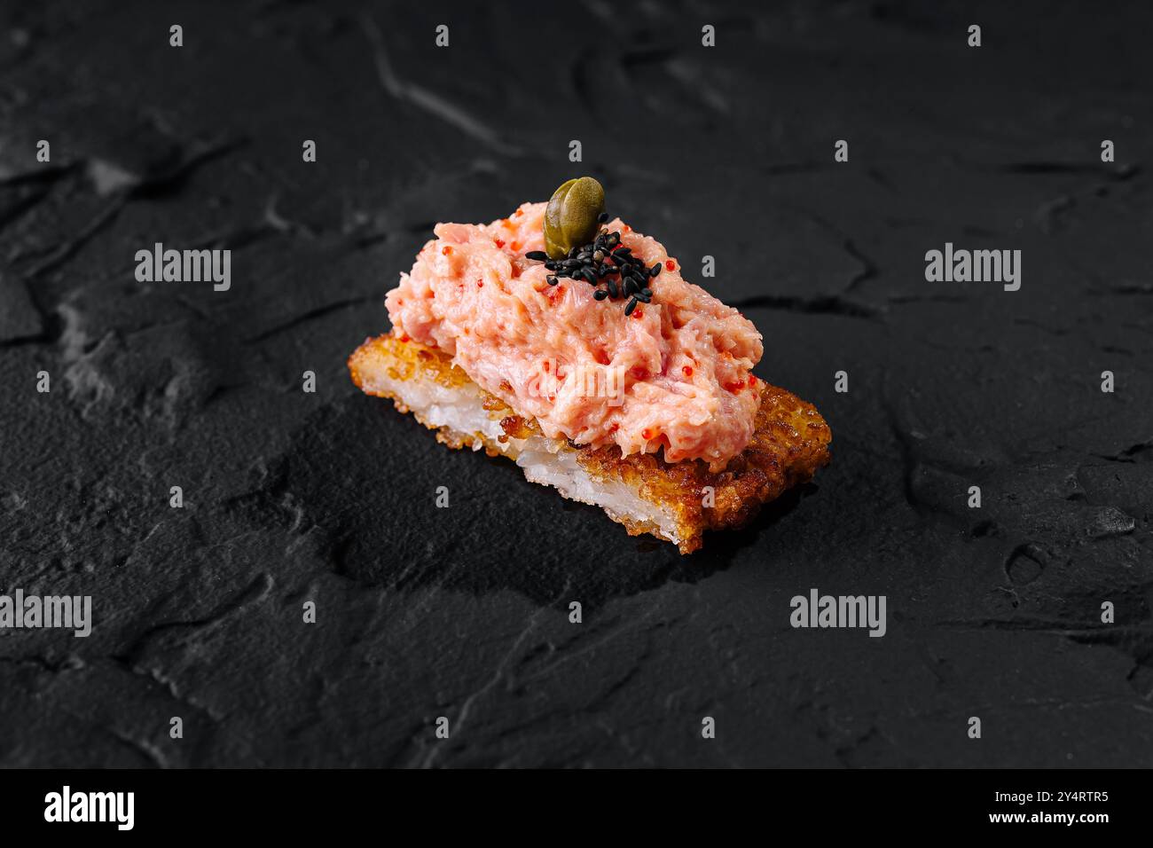Elegant salmon tartare on a crispy rice base, garnished with capers ...