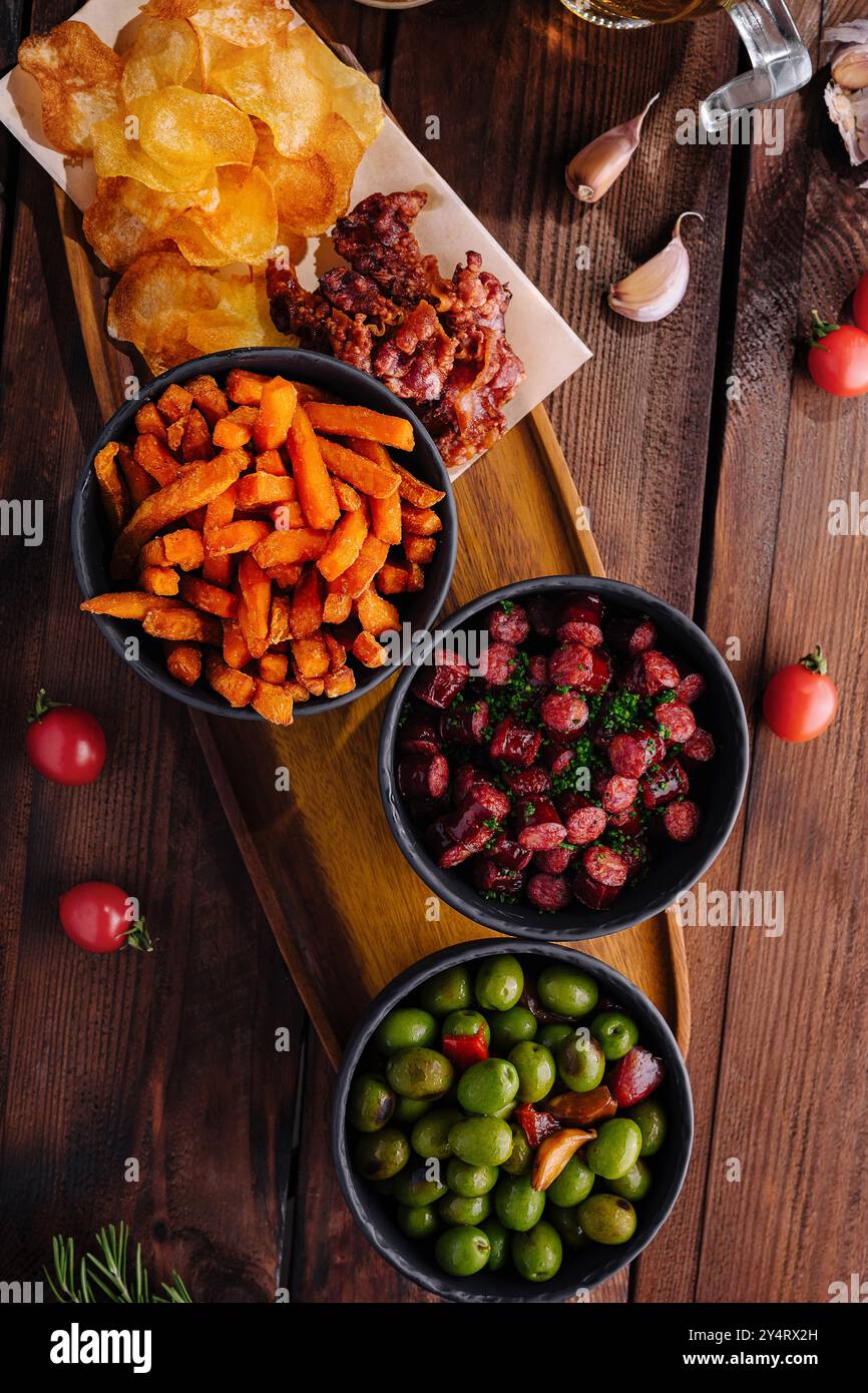 Elevated view of savory snacks including nuts, chips, and olives ...