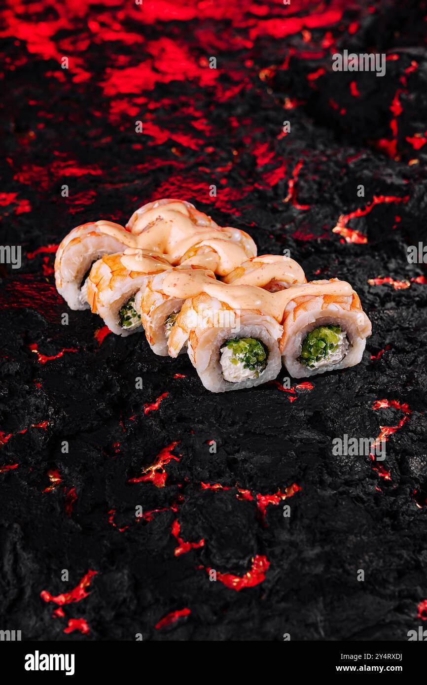 Gourmet sushi rolls with spicy drizzle on a unique black lava textured ...