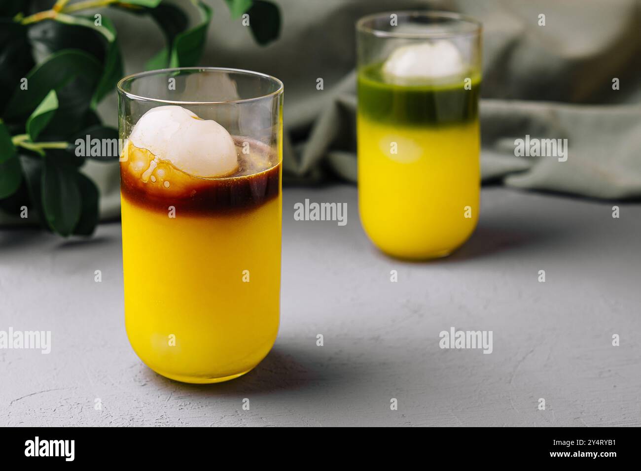 Elegant glasses with layered tropical cocktails and ice sphere Stock ...