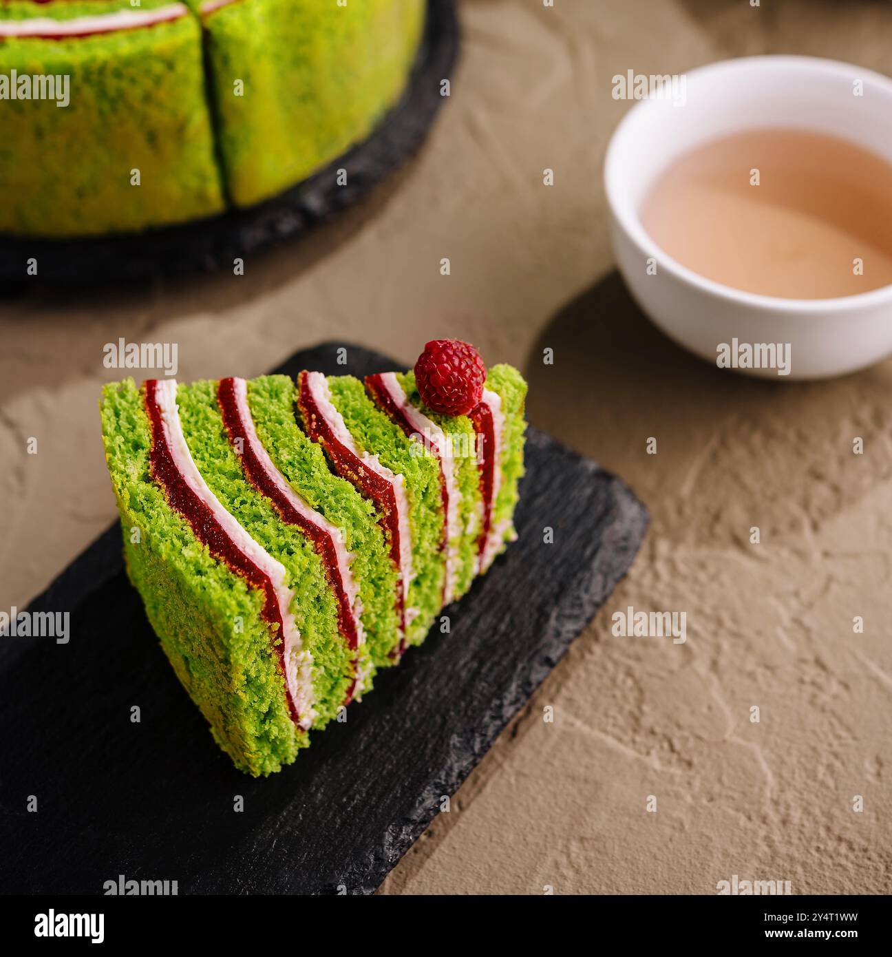 Slice of vibrant green tea matcha cake, decorated with raspberries ...
