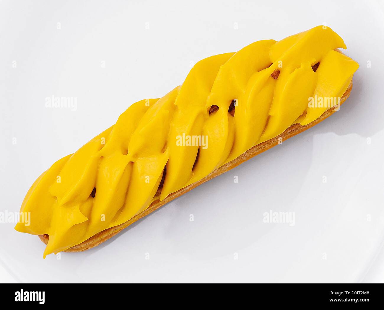 Vibrant mango eclair presented on a pure white circular plate, isolated ...